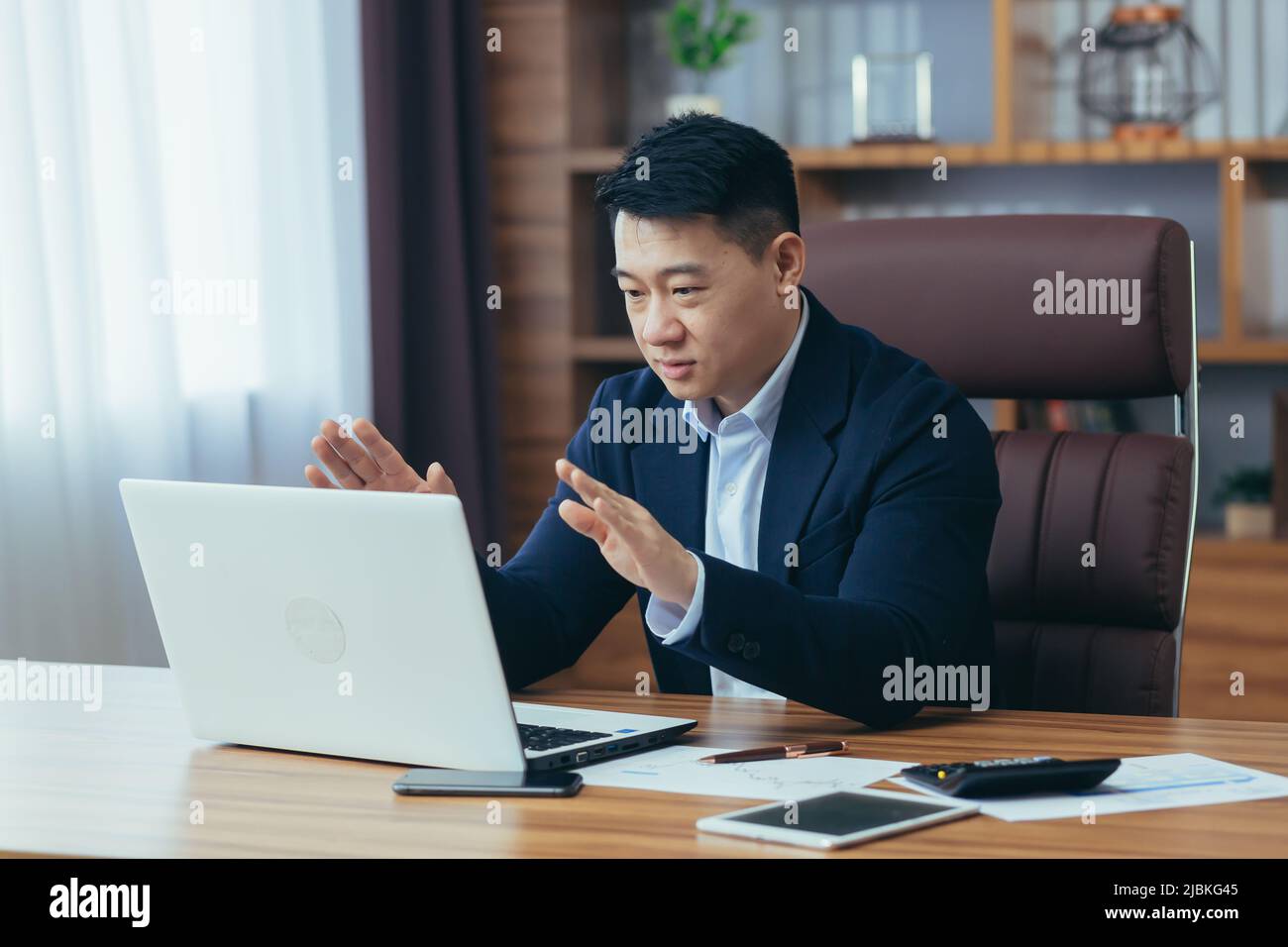 Asian businessman boss talking to colleagues on video call, looking at ...