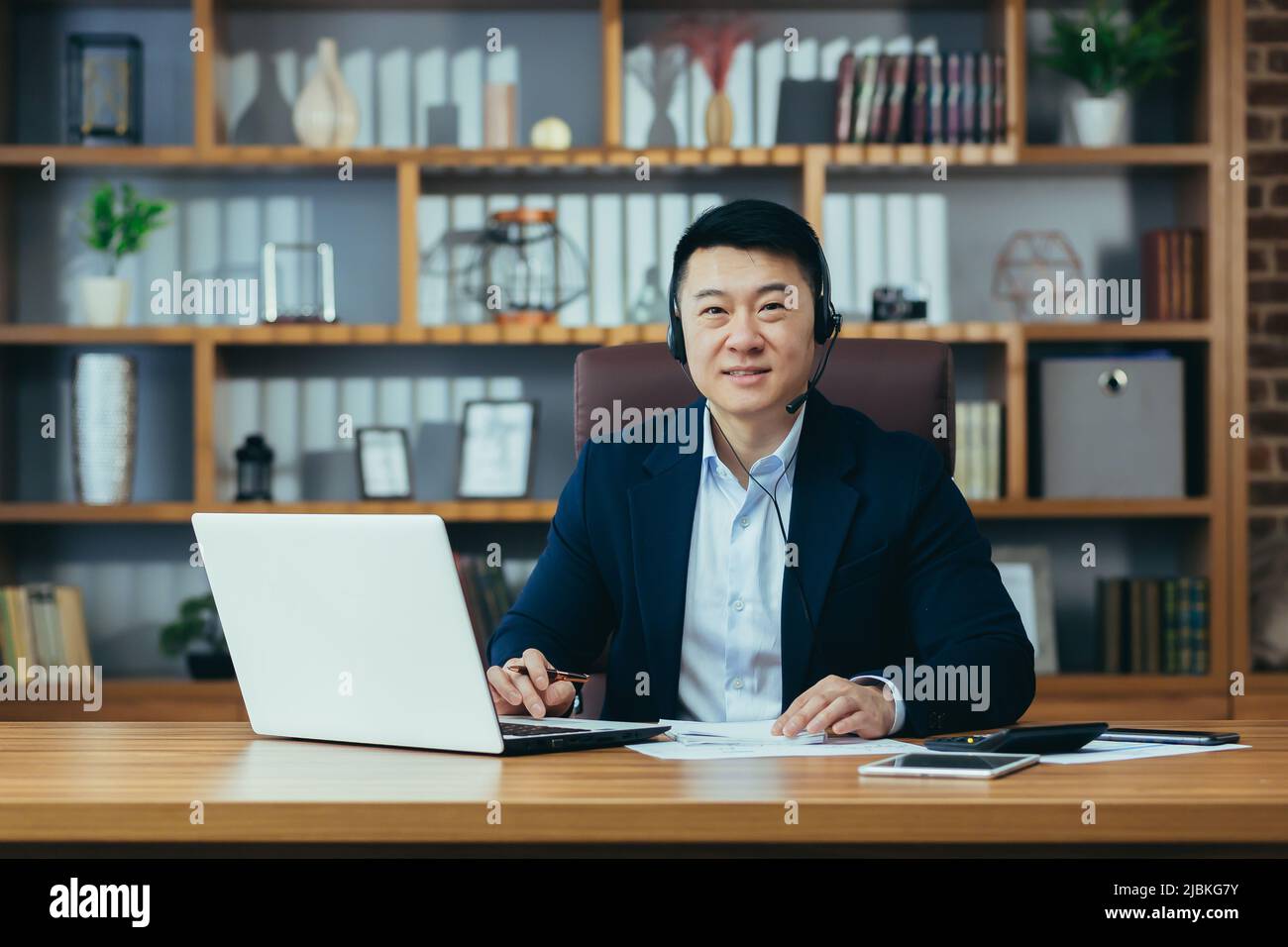 Asian business teacher teaches students online, uses headset and laptop ...