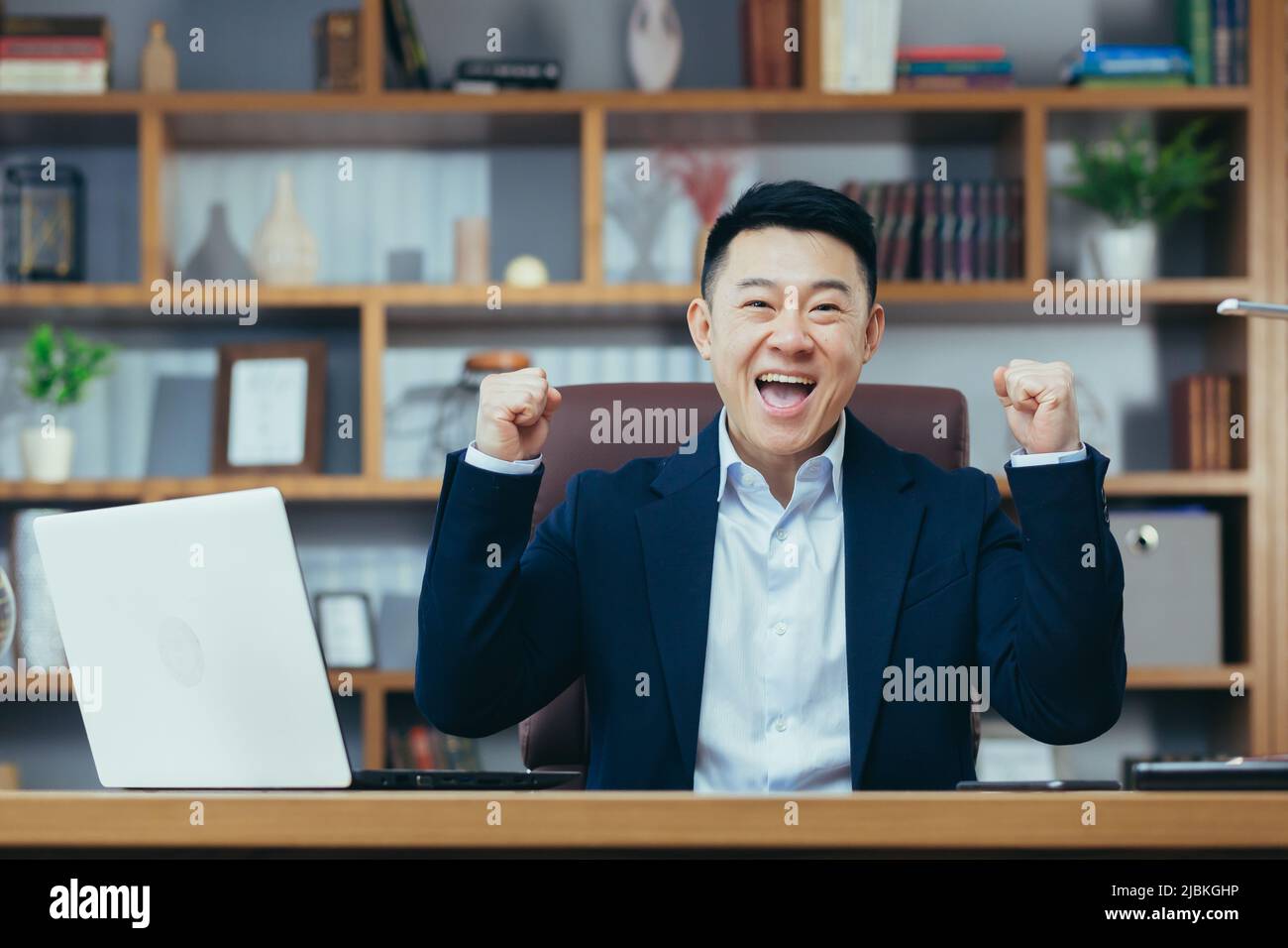 Happy Asian boss looks at camera and celebrates business victory, holds ...