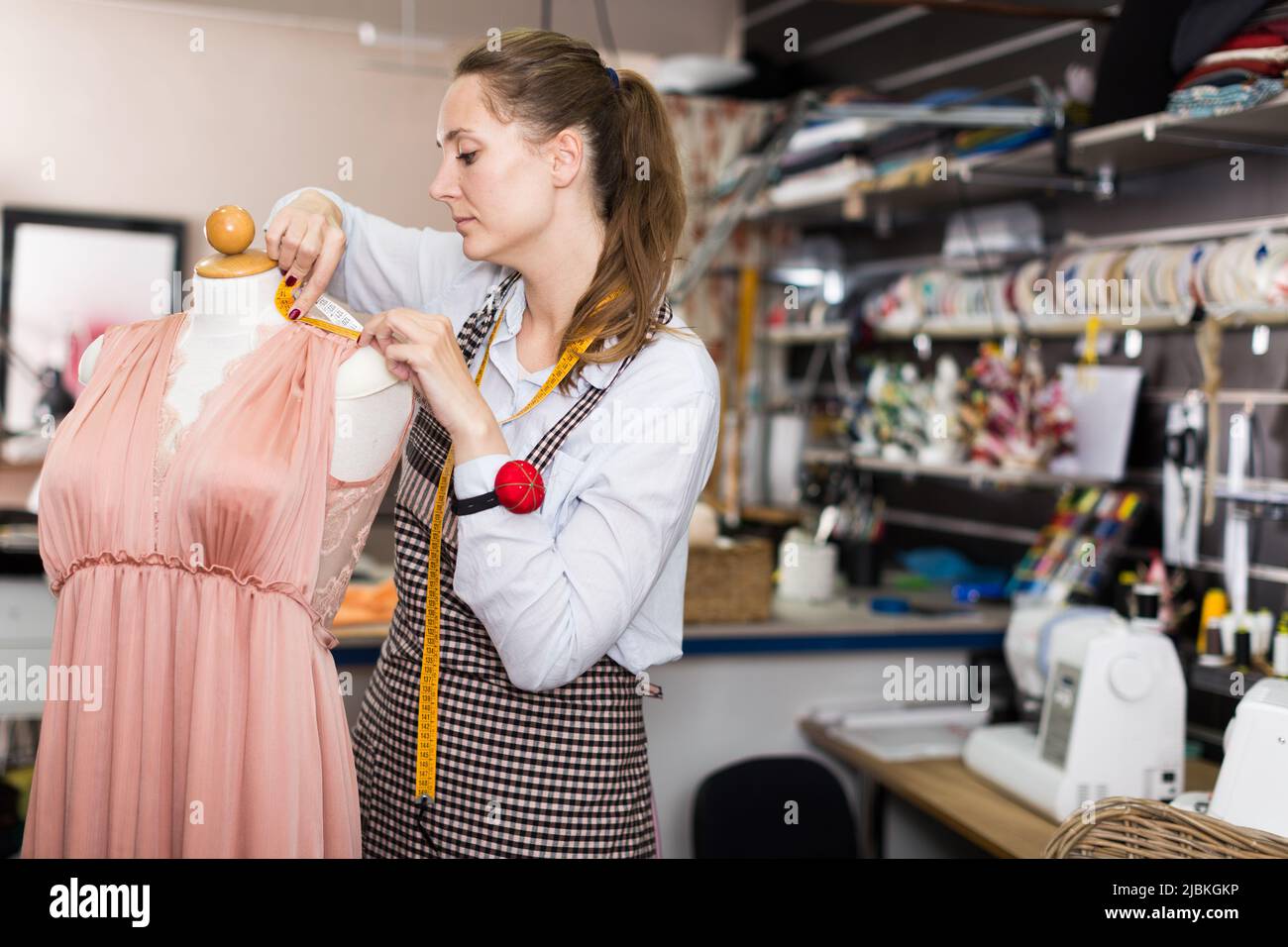 Female seamstress is thinking about new dress for collection of clothes ...