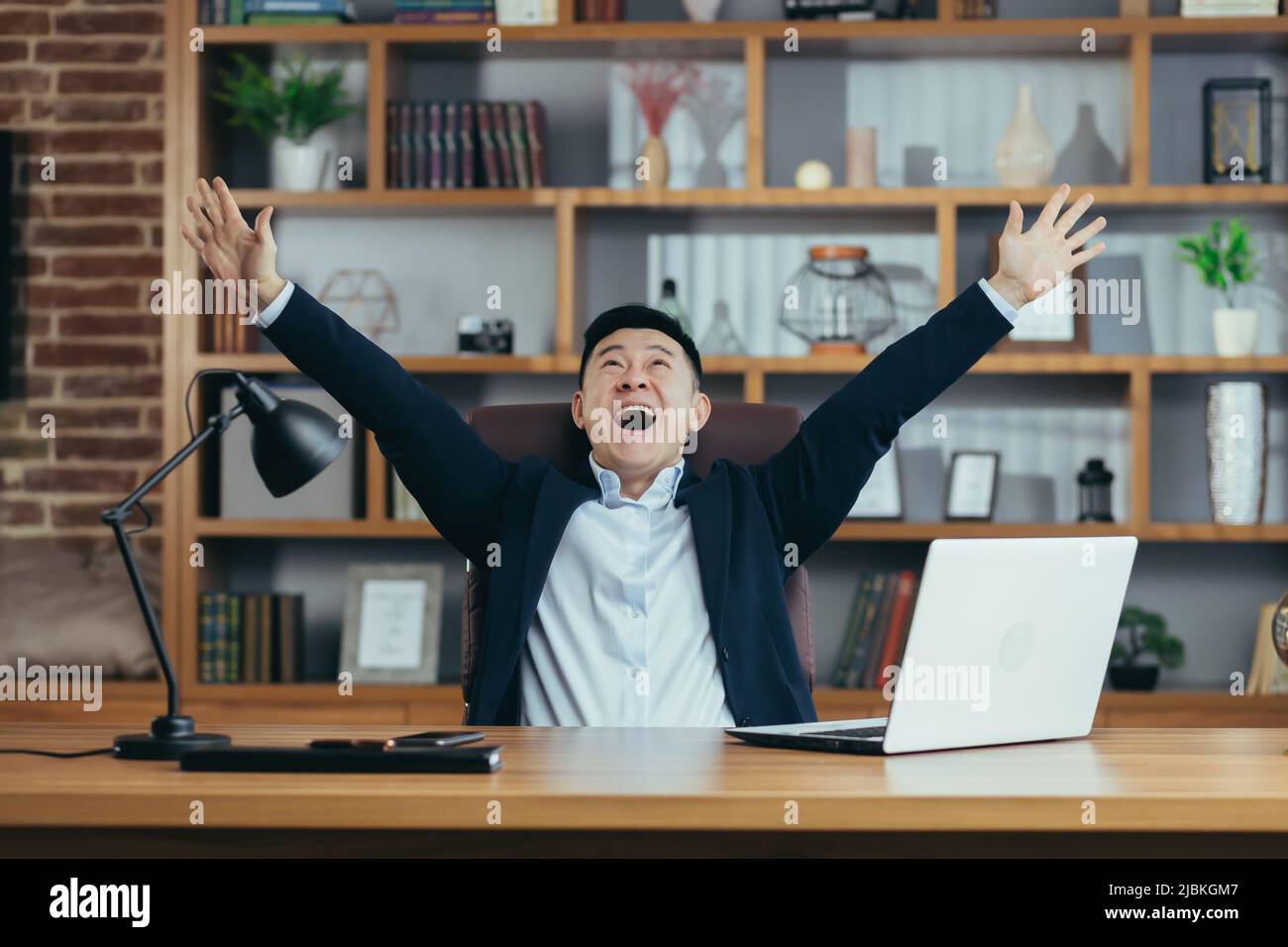 Happy Asian boss looks at camera and celebrates business victory, holds ...