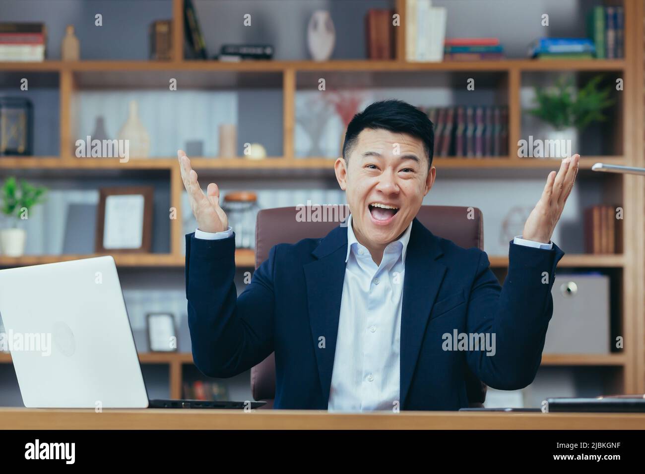 Successful Asian banker rejoices, holds hands up celebrates victory ...