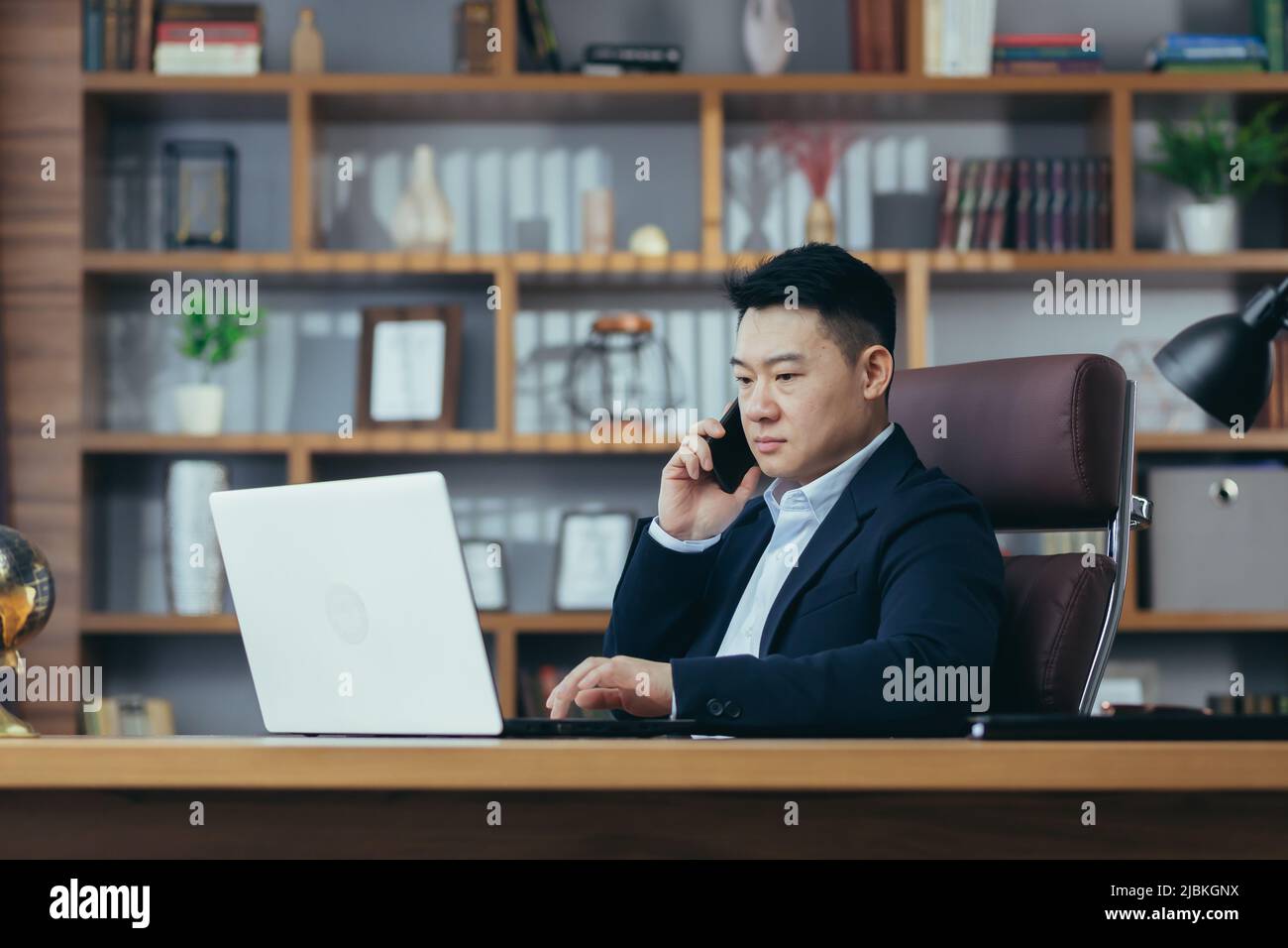 Serious and pensive Asian businessman, boss, working in a classic ...