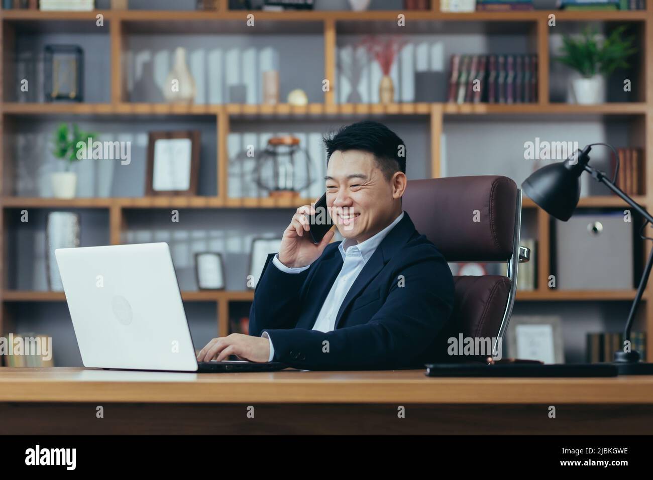 Happy asian boss banker talking on the phone working in a classic ...