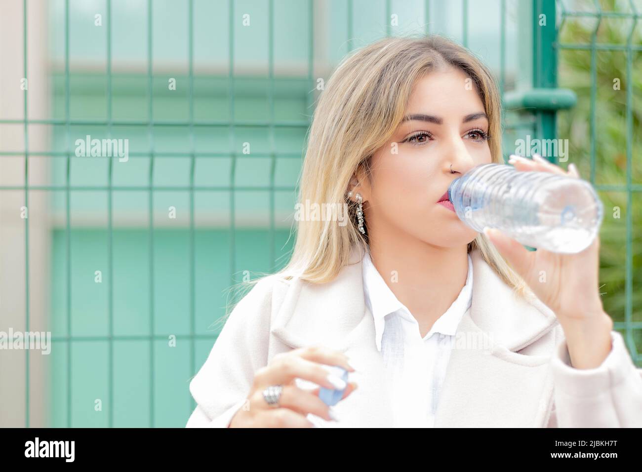business woman drinking water on the street in front of an office ...