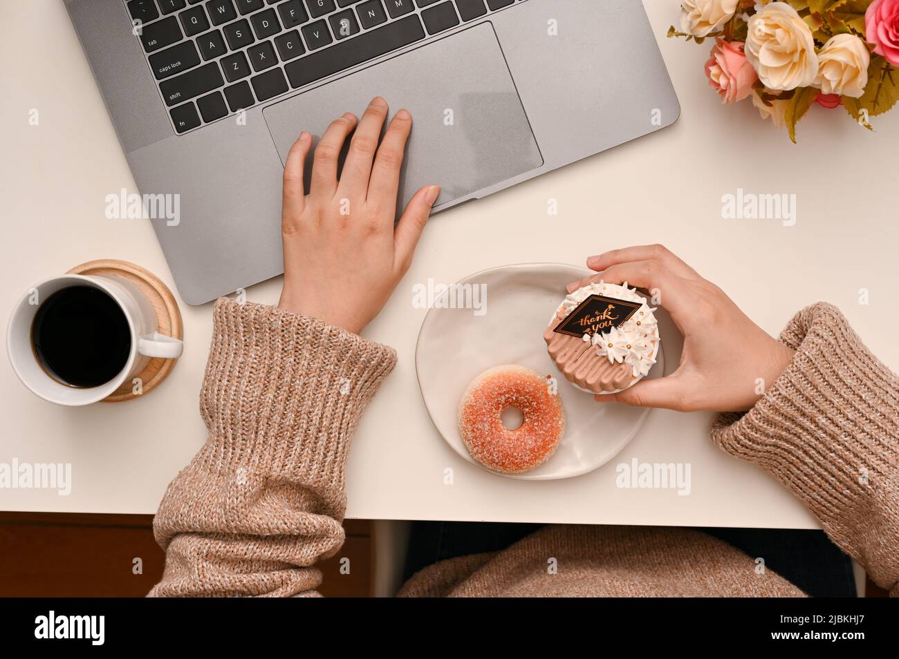 Top view of a relaxed woman in warm sweater eating delicious cupcake ...