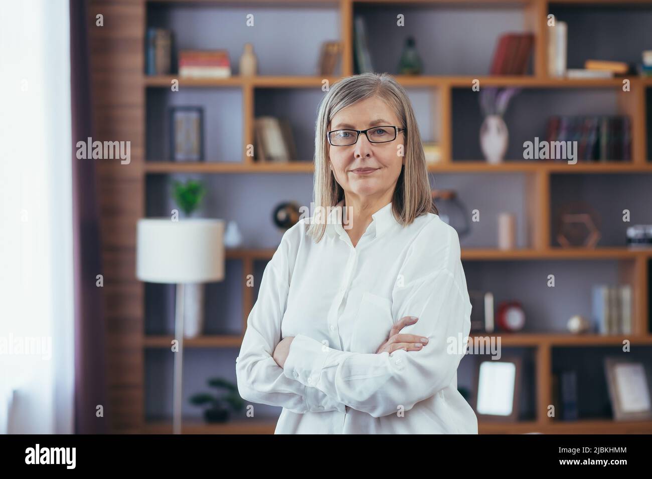 Senior woman in living room looking at camera and smiling, portrait of ...