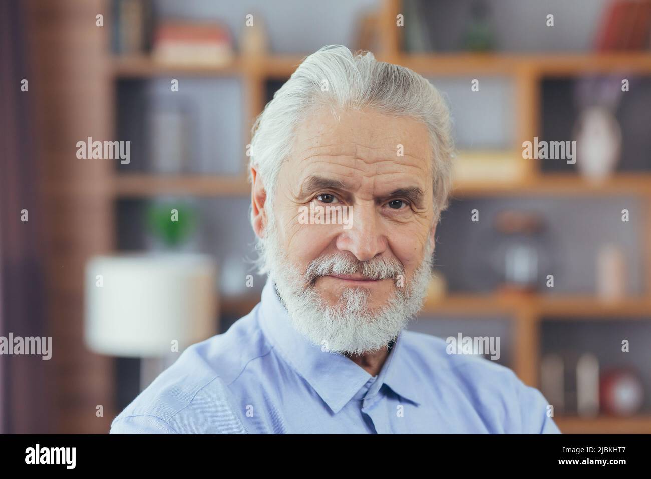 Close-up photo of portrait of old man at home, looking at camera and ...