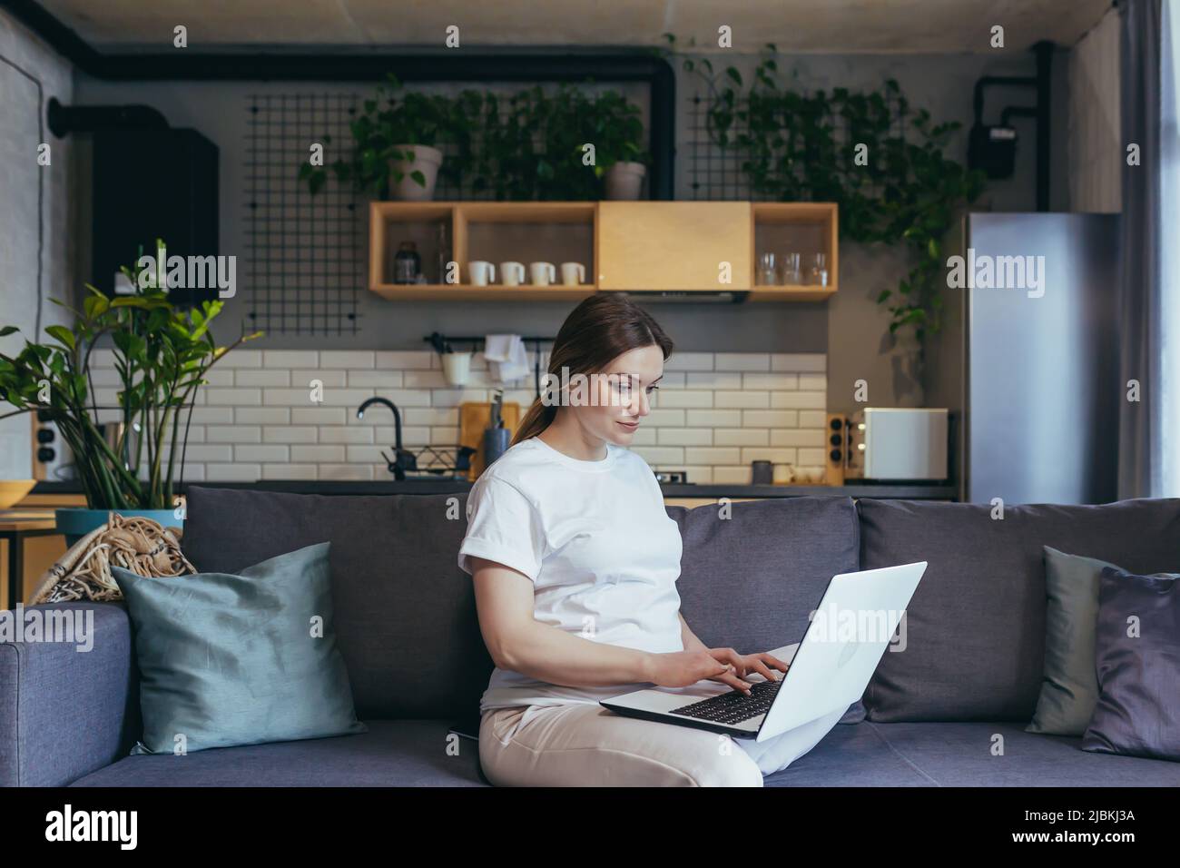 Maternity leave. Pregnant beautiful woman sitting on sofa at home with ...