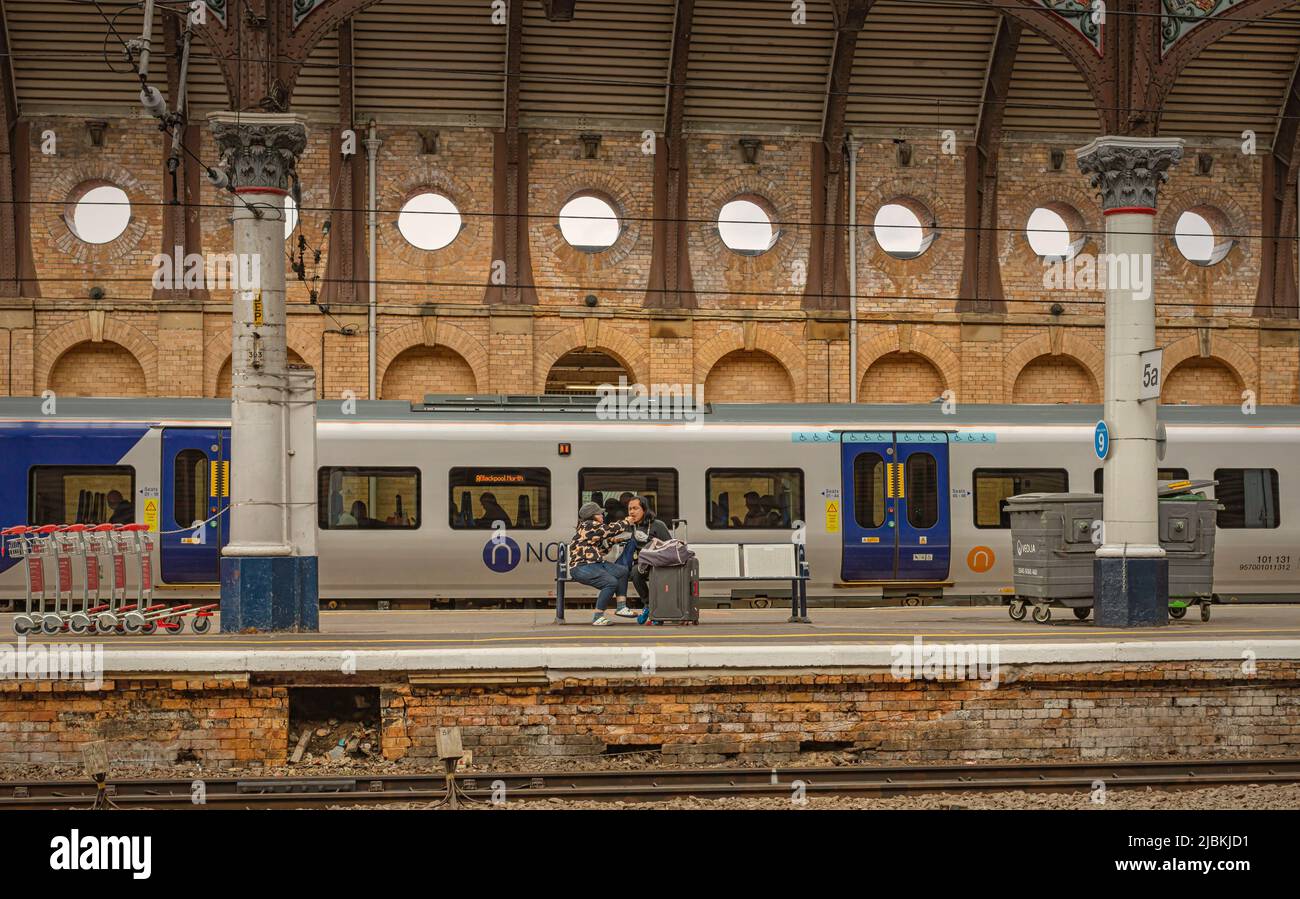 Passengers sit on a bench between two columns on a railway station ...