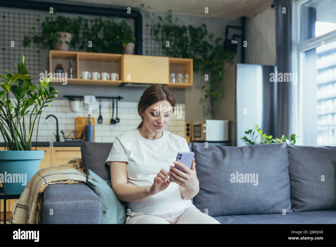 Maternity leave. Pregnant beautiful woman sitting on the couch at home ...