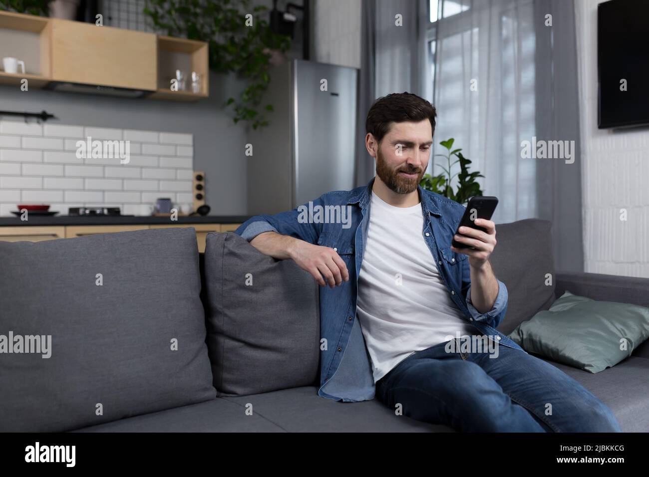 Thinking man looking at phone screen sitting on sofa at home Stock ...