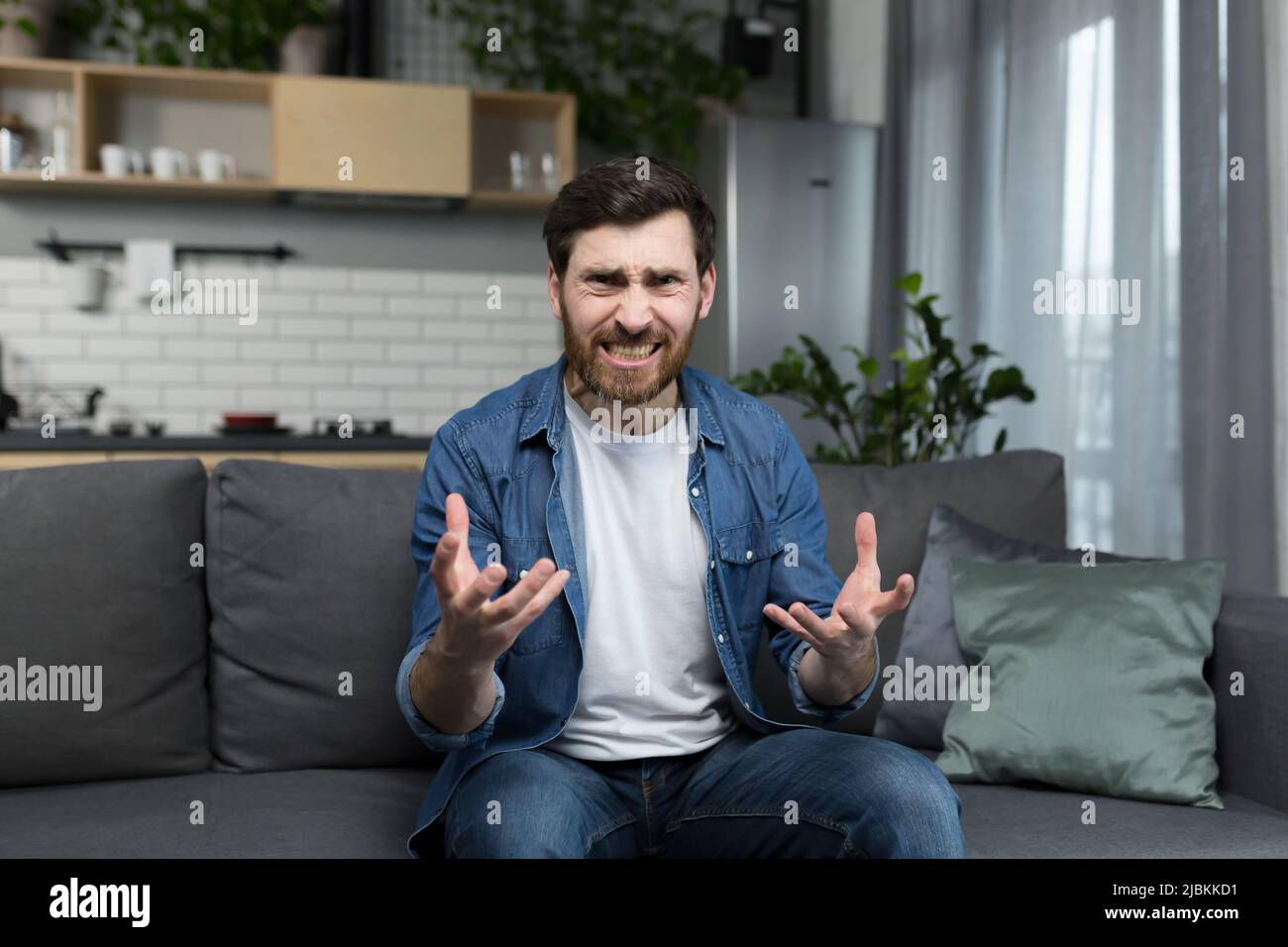 An angry man talking on a video call, looking at the webcam, angrily ...