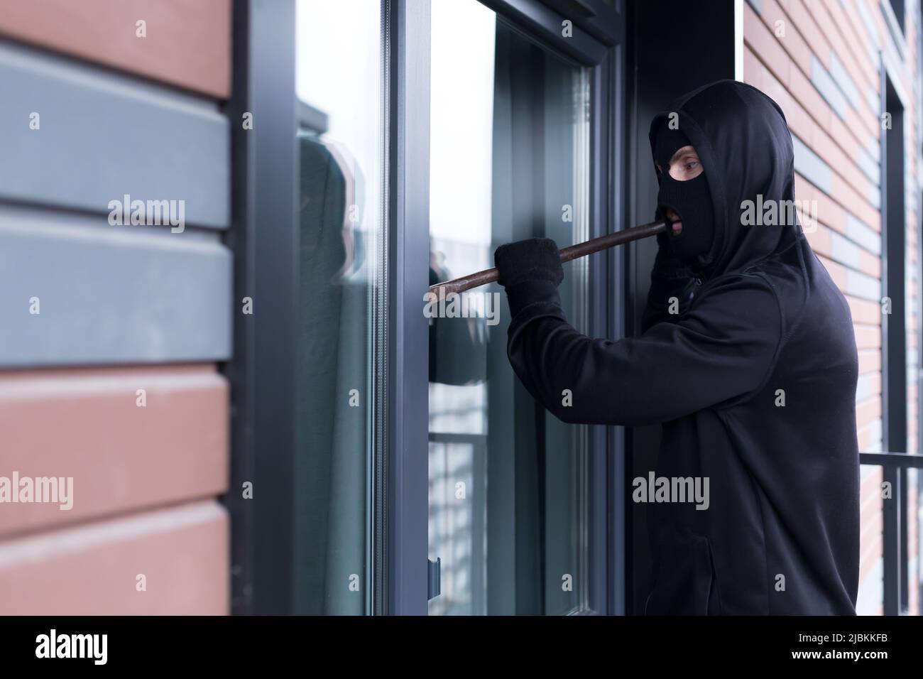 A burglar man tries to break the door lock and get into the apartment ...
