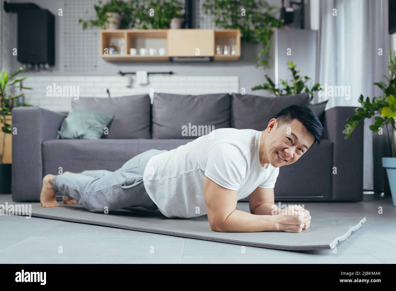 Asian performs morning exercises, bar on the floor, male athlete ... Asian performs morning exercises, bar on the floor, male athlete ...