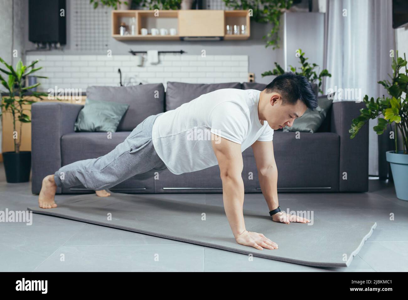 Asian performs morning exercises, bar on the floor, male athlete ... Asian performs morning exercises, bar on the floor, male athlete ...