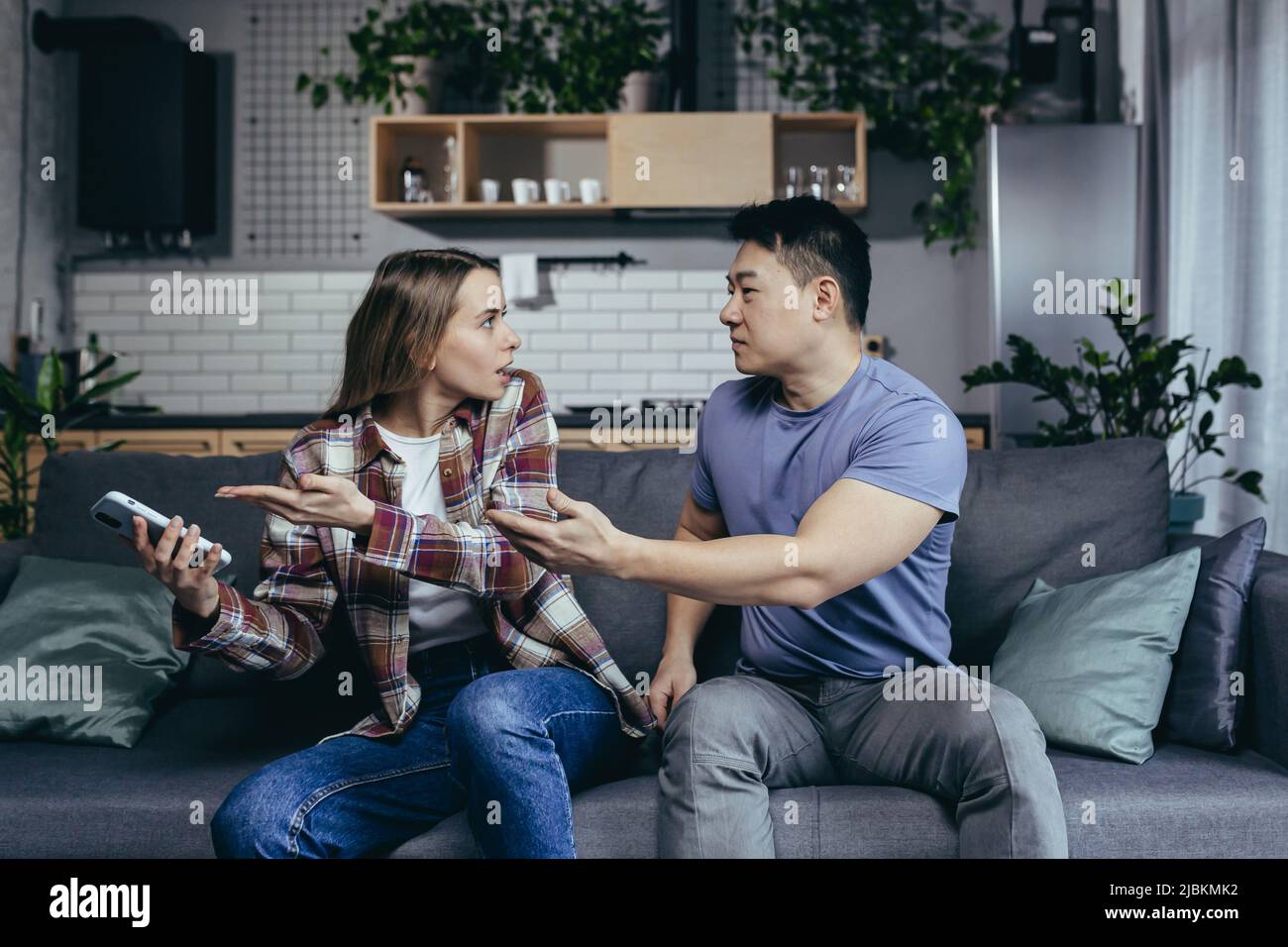 Married couple, man and woman, sitting on the couch at home and arguing ...