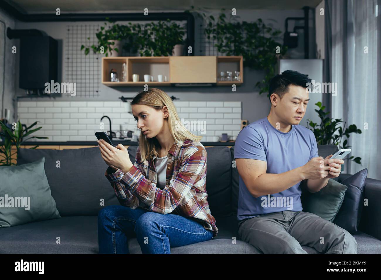 Young multiracial family, quarreling sitting on the couch in the room ...
