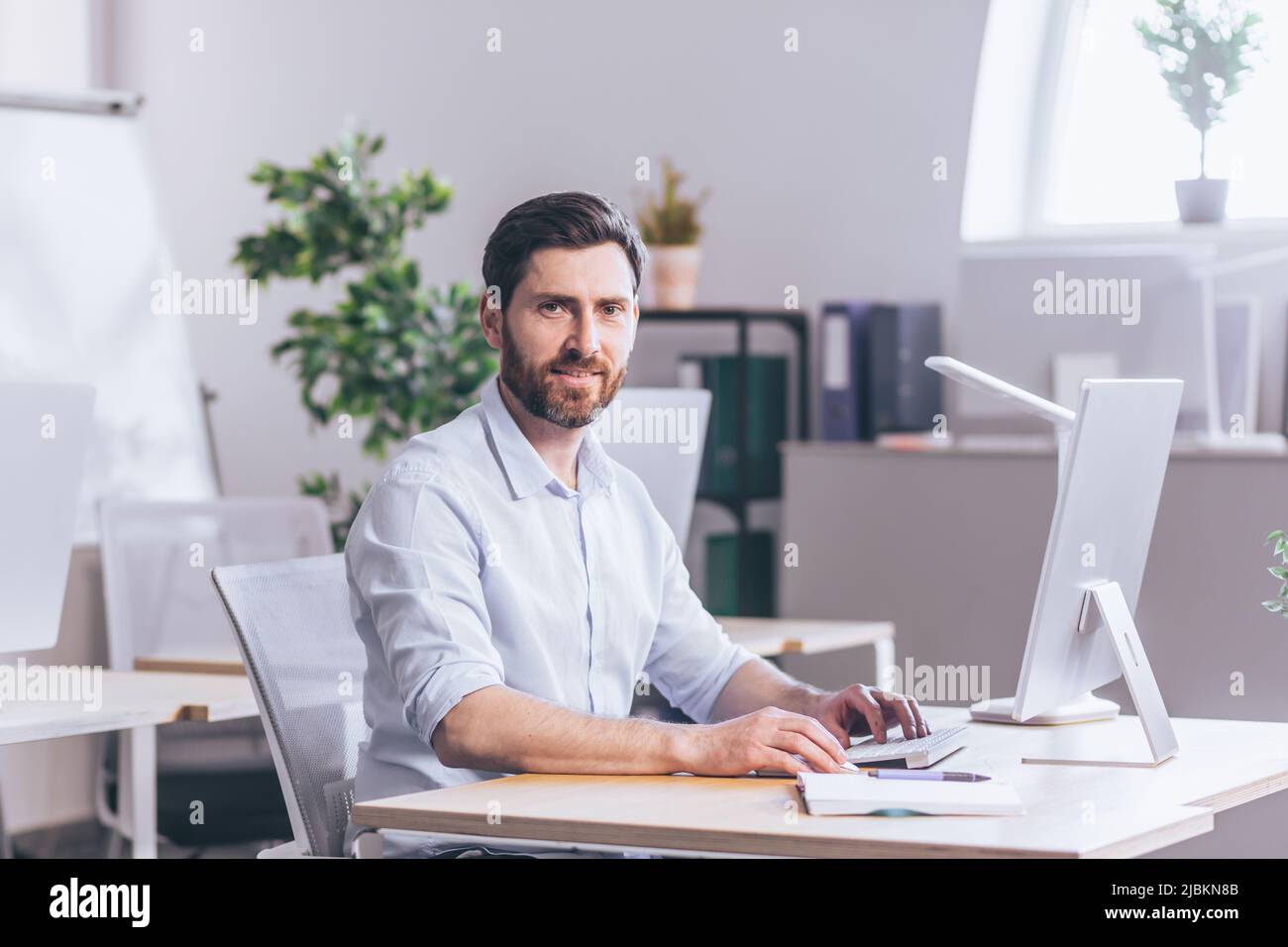 Successful bearded freelance businessman looks at camera and smiles ...