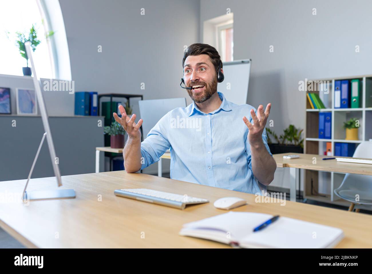 A happy surprised call center employee works in the office with a ...