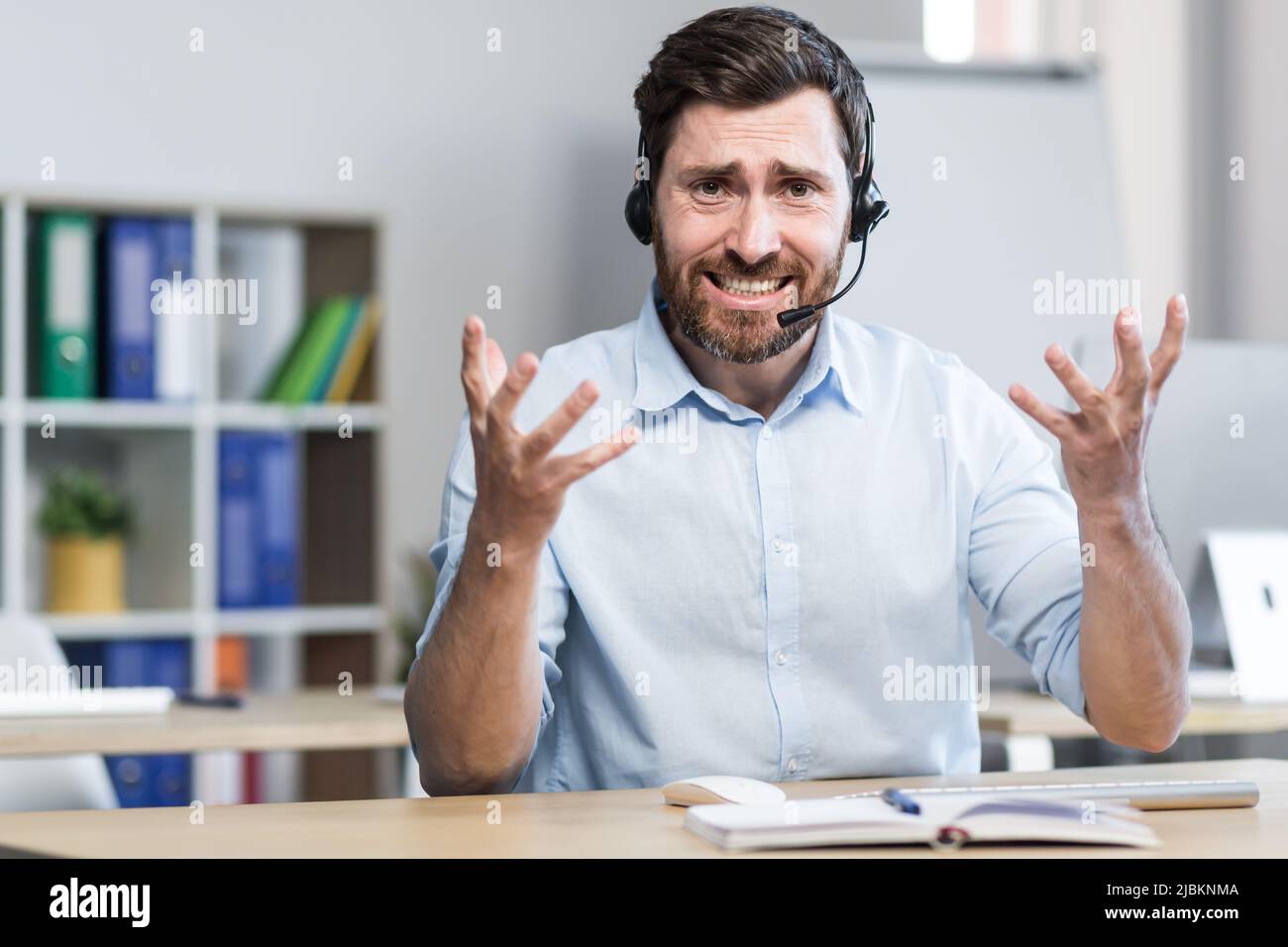 Annoyed call center employee looks at the camera and quarrels with the ...