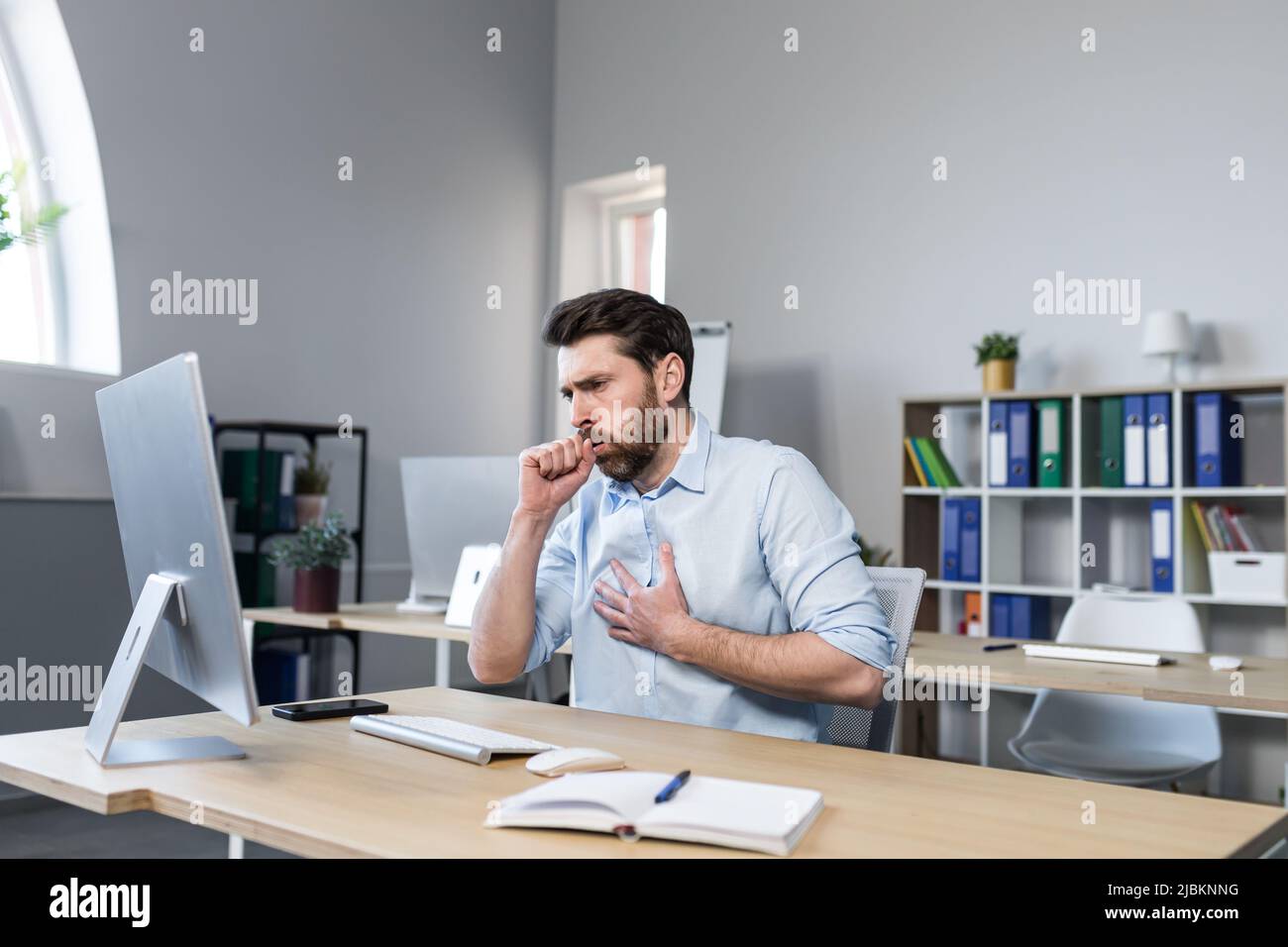 Sick man working in the office, has a bad cough, coughing businessman ...