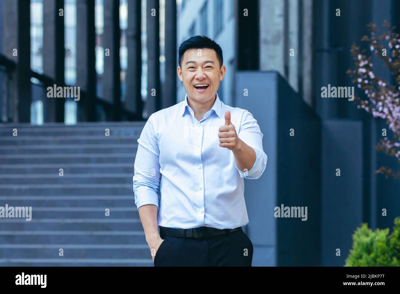 Happy asian agent businessman looking at camera and smiling holding ...