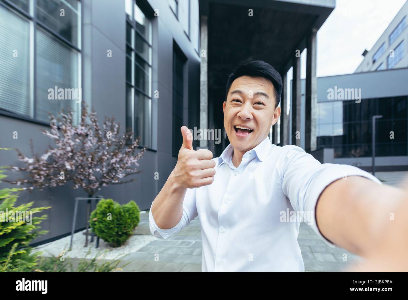 Asian student making selfie looking at phone screen and smiling, video ...