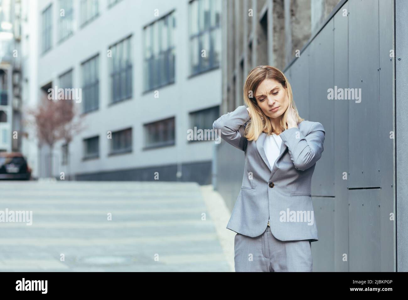Woman near the office has severe back and neck pain, fatigue and ...