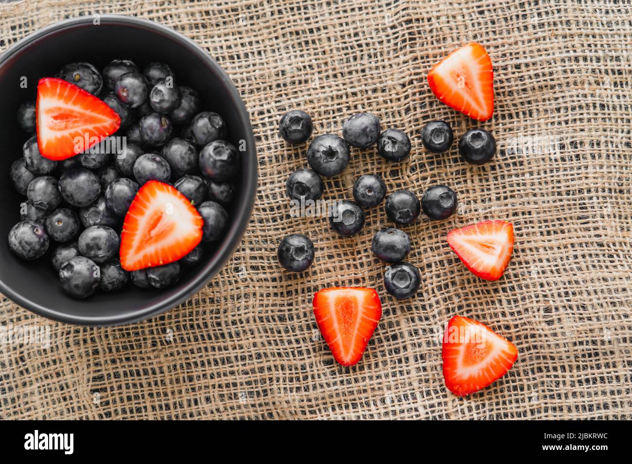 Top view of whole blueberries and cut strawberries on sackcloth Stock ...