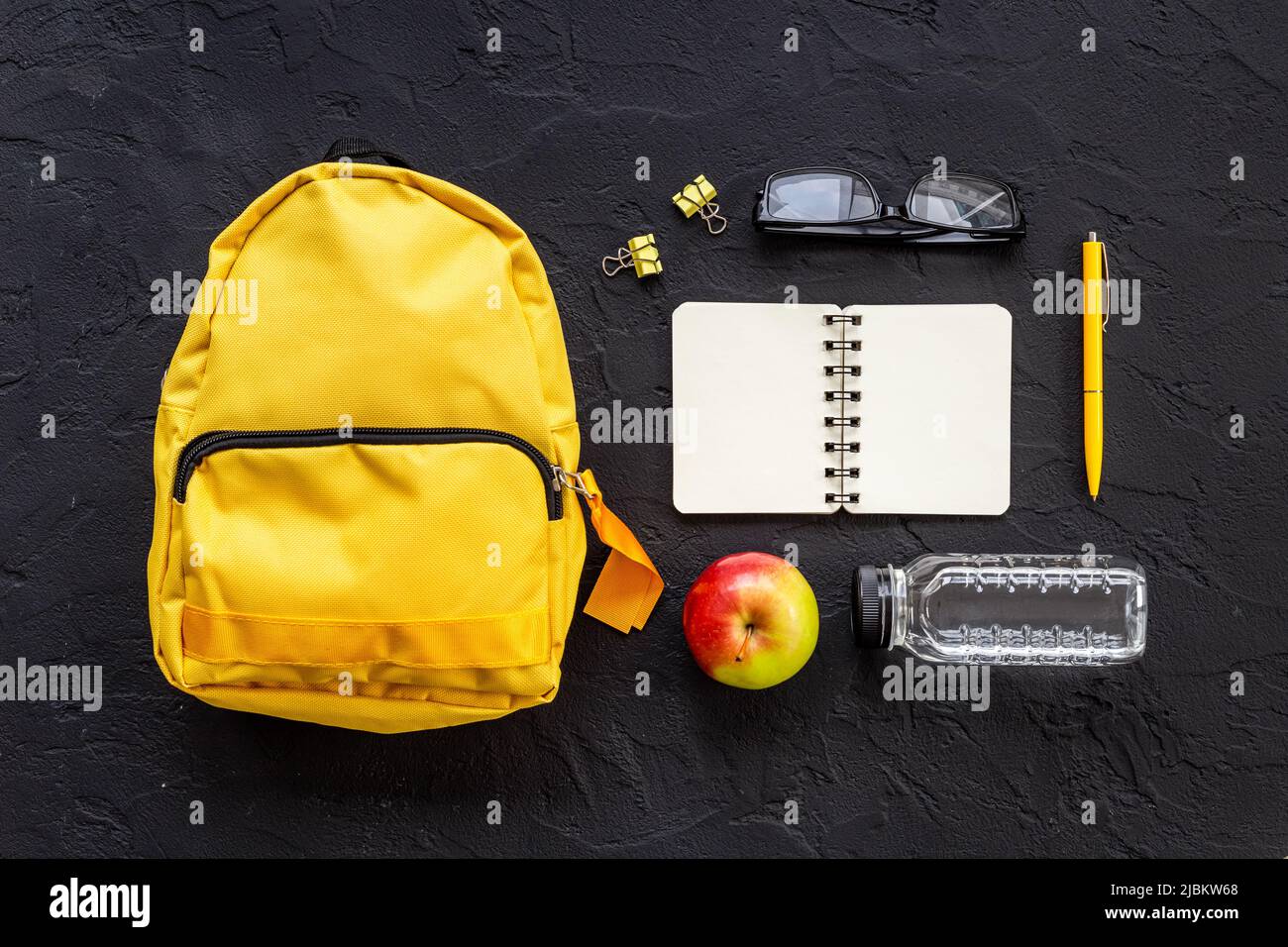 Back to school concept. Yellow school backpack with supplies water and ...