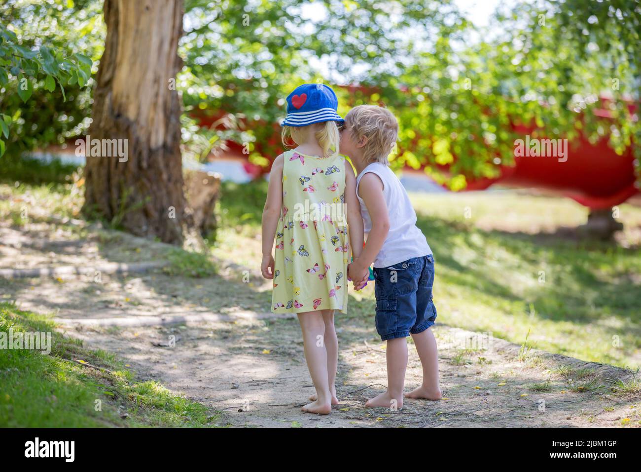 Sweet toddler kids, walking together hand in hand on a little path next ...