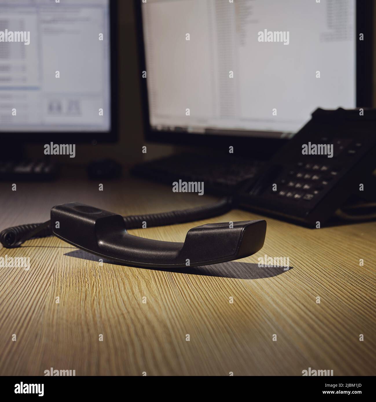 Handset of the landline phone lies on the office desk with computer ...