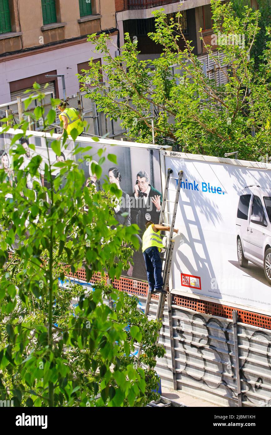 Man placing advertising poster on an advertising billboard in Barcelona ...