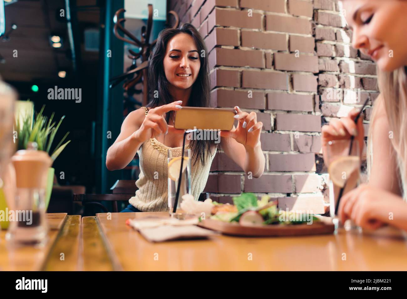 Two girlfriends having healthy lunch in cafe. Young woman taking ...