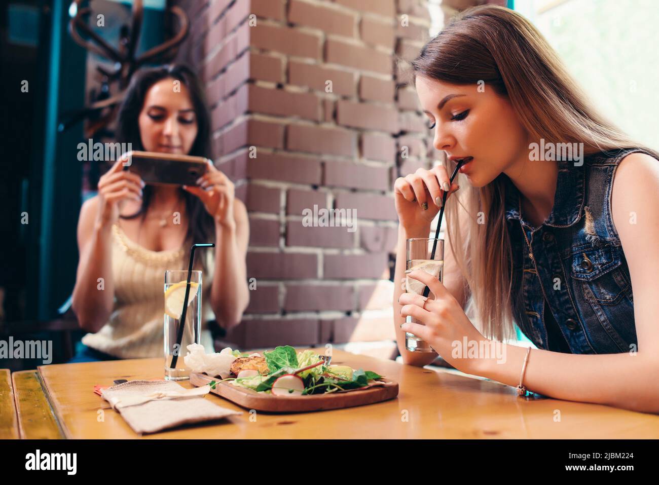 Two girlfriends having healthy lunch in cafe. Young woman taking ...