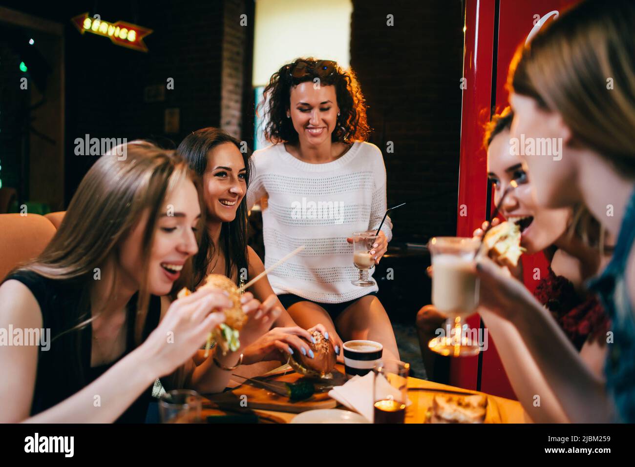 Group of young girlfriends having lunch in fast food restaurant eating ...