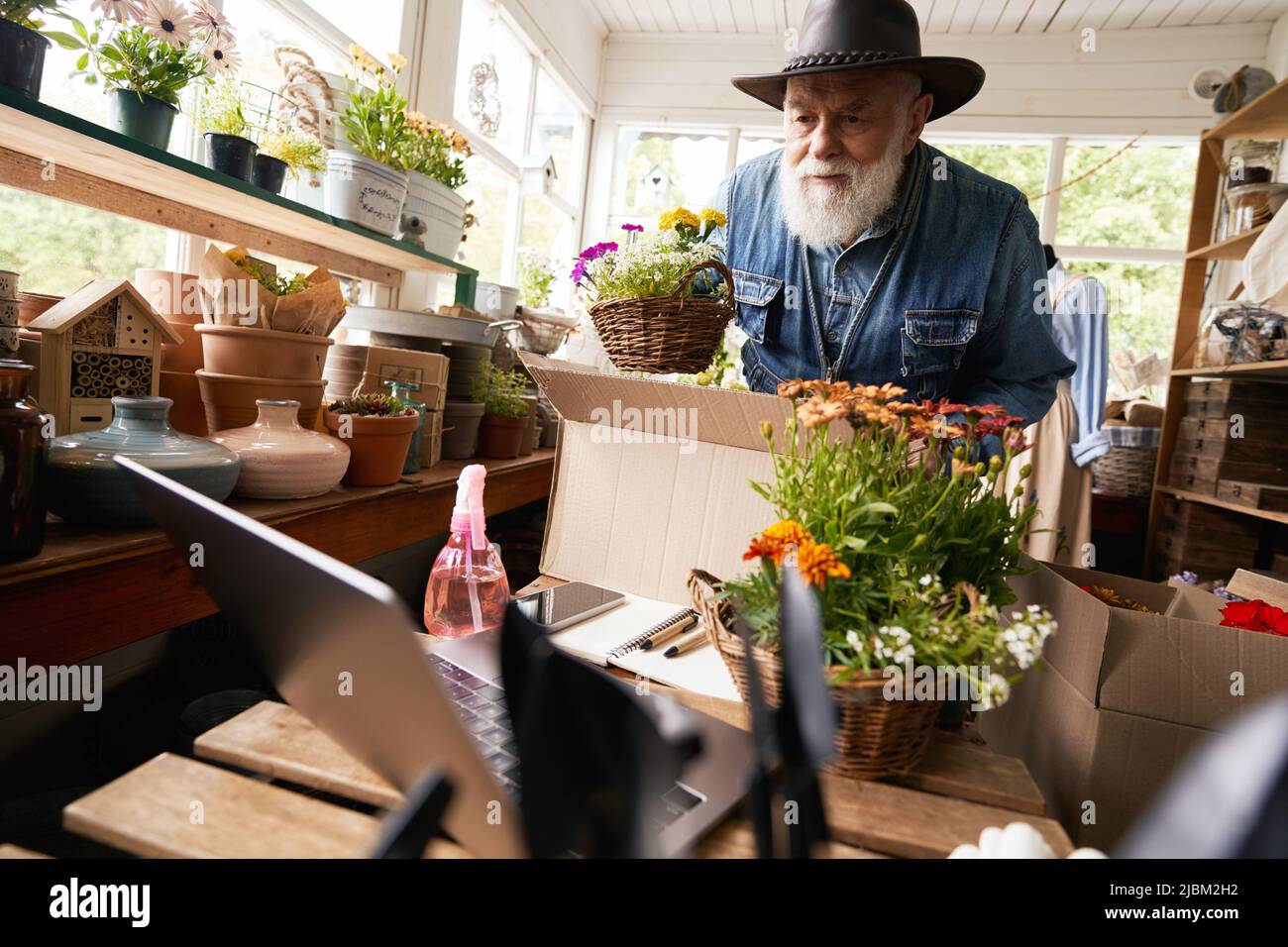 Florist with laptop packing wicker baskets into cardboard Stock Photo ...