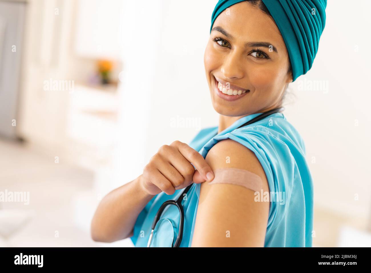 Portrait of smiling biracial young female doctor in hijab showing ...