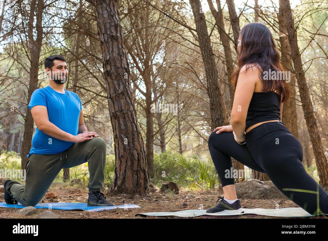Young friends stretch on their yoga mats at sunset in a forest ...