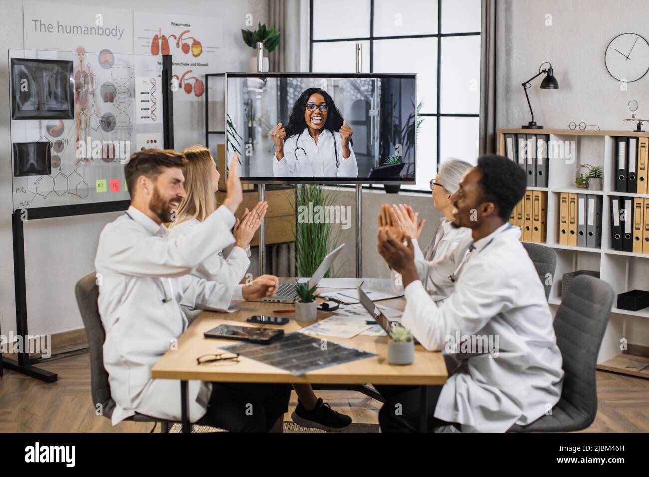 Team of multicultural doctors in white lab coats clapping hands during ...