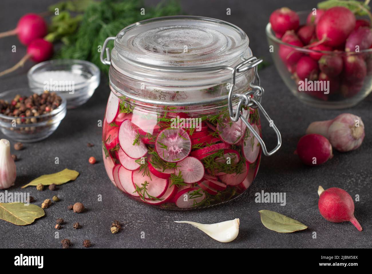 Marinated radish with dill and garlic in glass jar on dark gray ...