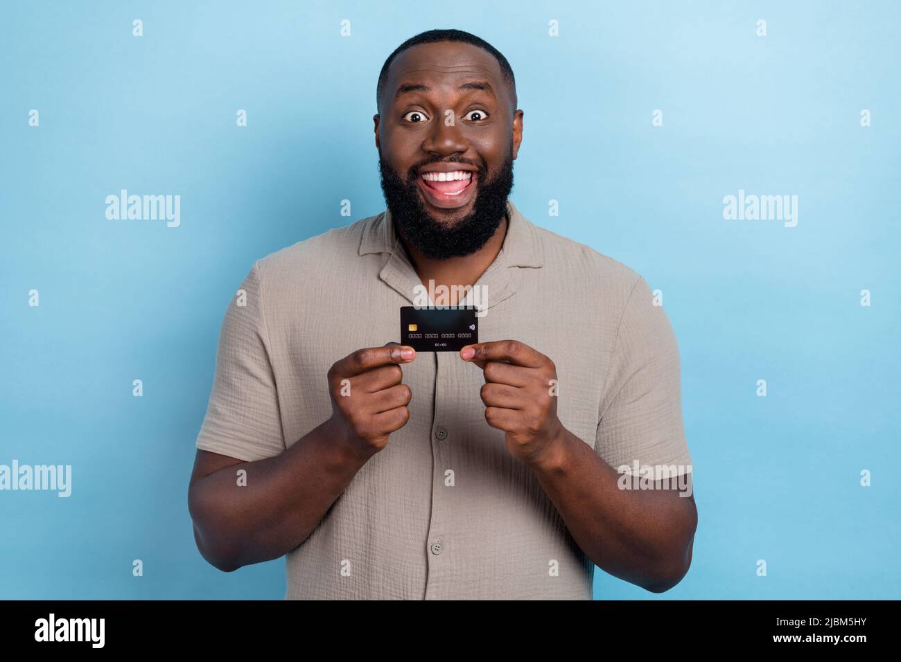Portrait of astonished excited guy hold demonstrate plastic debit card ...