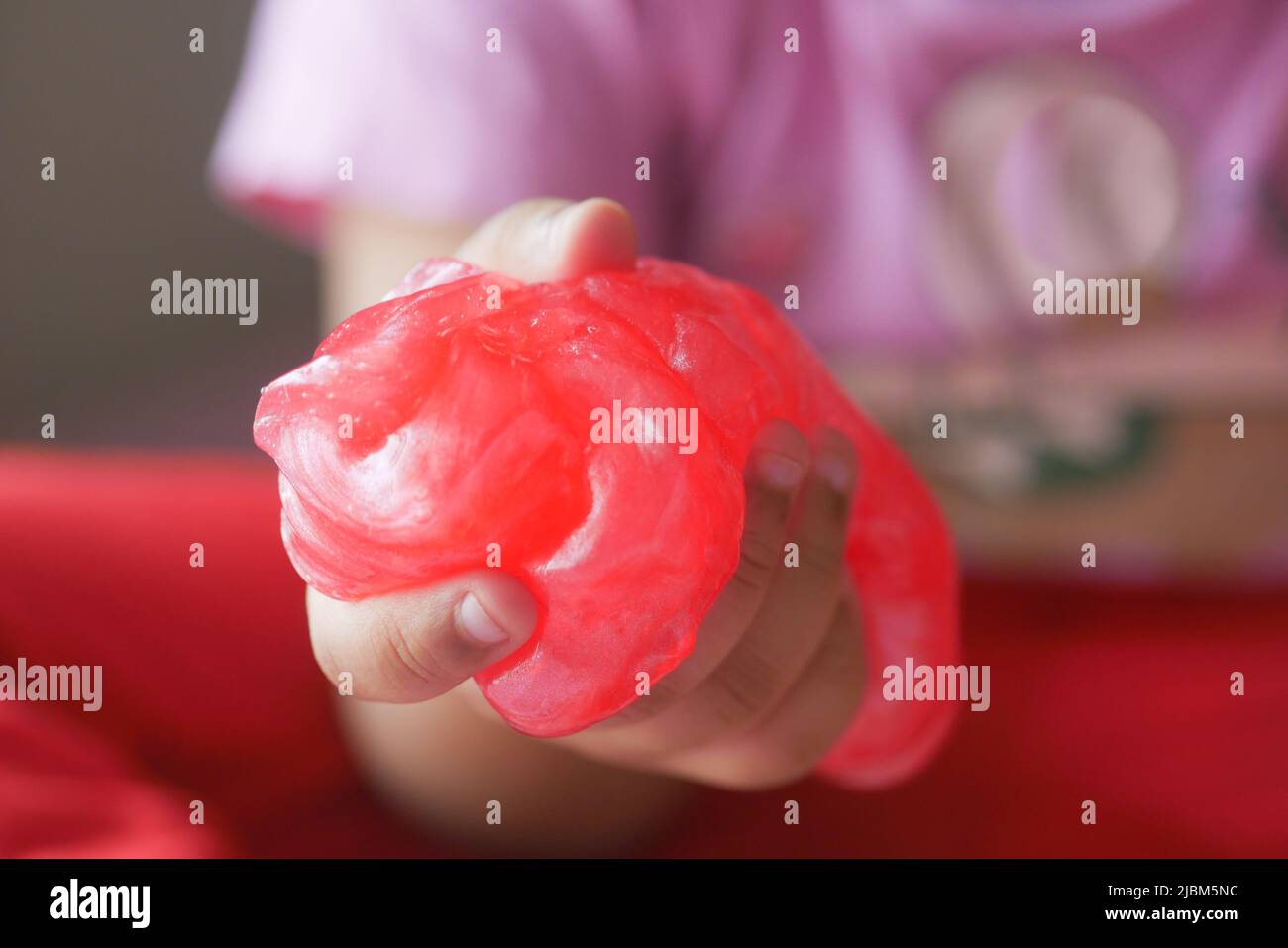 child Hand holding pink color slime Stock Photo - Alamy