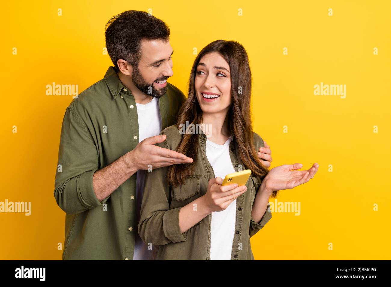 Portrait of attractive cheerful couple using device talking discussing ...