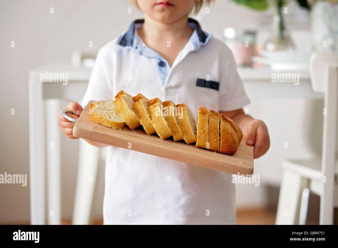 Child, blond toddler boy, holding wooden cutting board with homemade ...