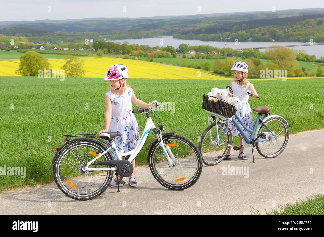 Twin sisters are seen riding their bicycles in the countryside. They ...