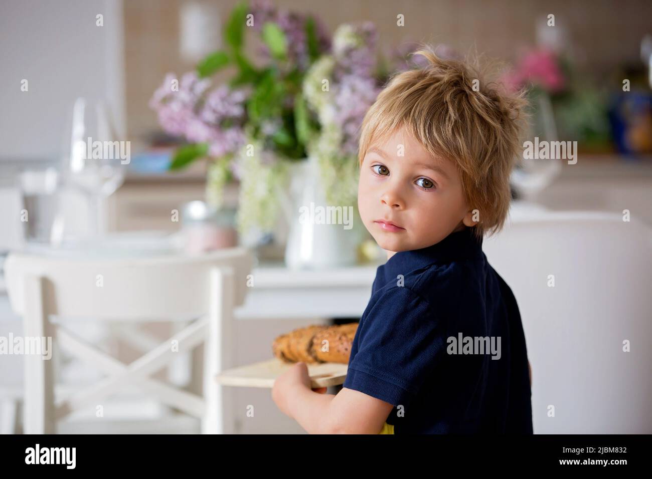 Child, blond toddler boy, holding wooden cutting board with homemade ...