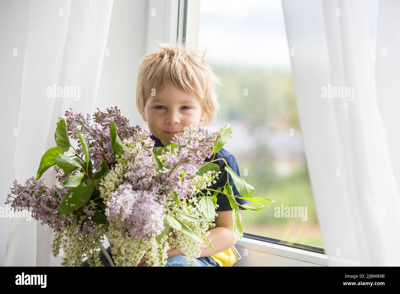 Close portrait of a beautiful blond child, toddler boy with vase with ...