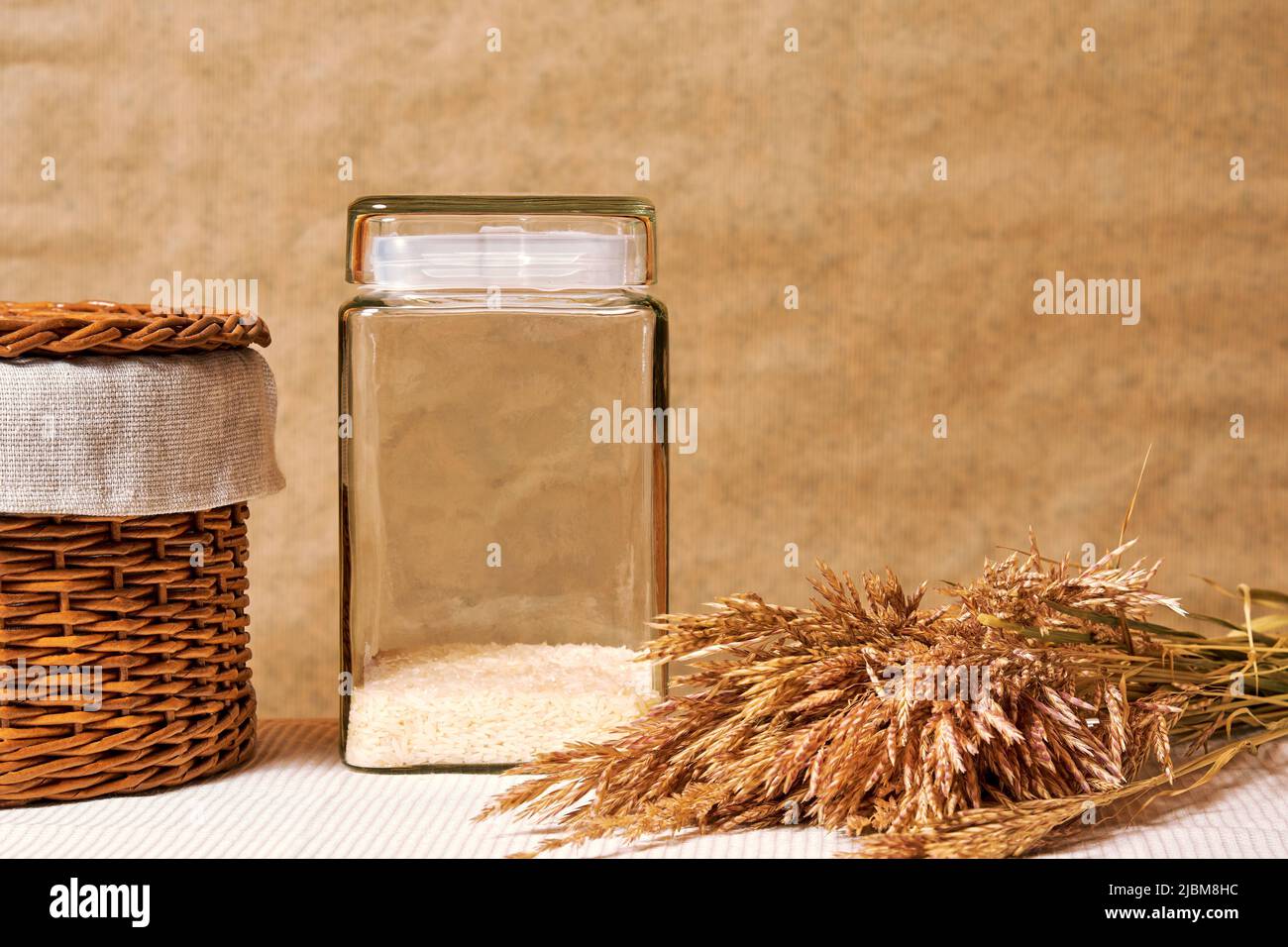 Dry white rice in the transparent jar on the kitchen with basket and ...